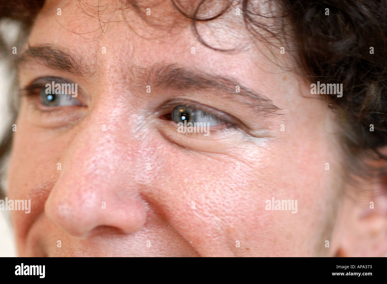 Close up smiling eyes eyebrows nose dark curly hair left ear looking ...