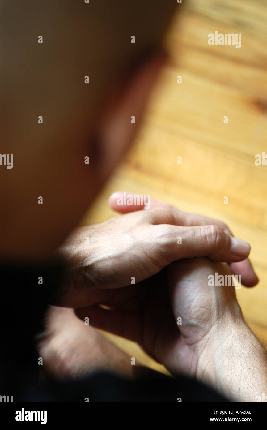Clasped hands and side of head over right shoulder wood floor bkgrnd ...