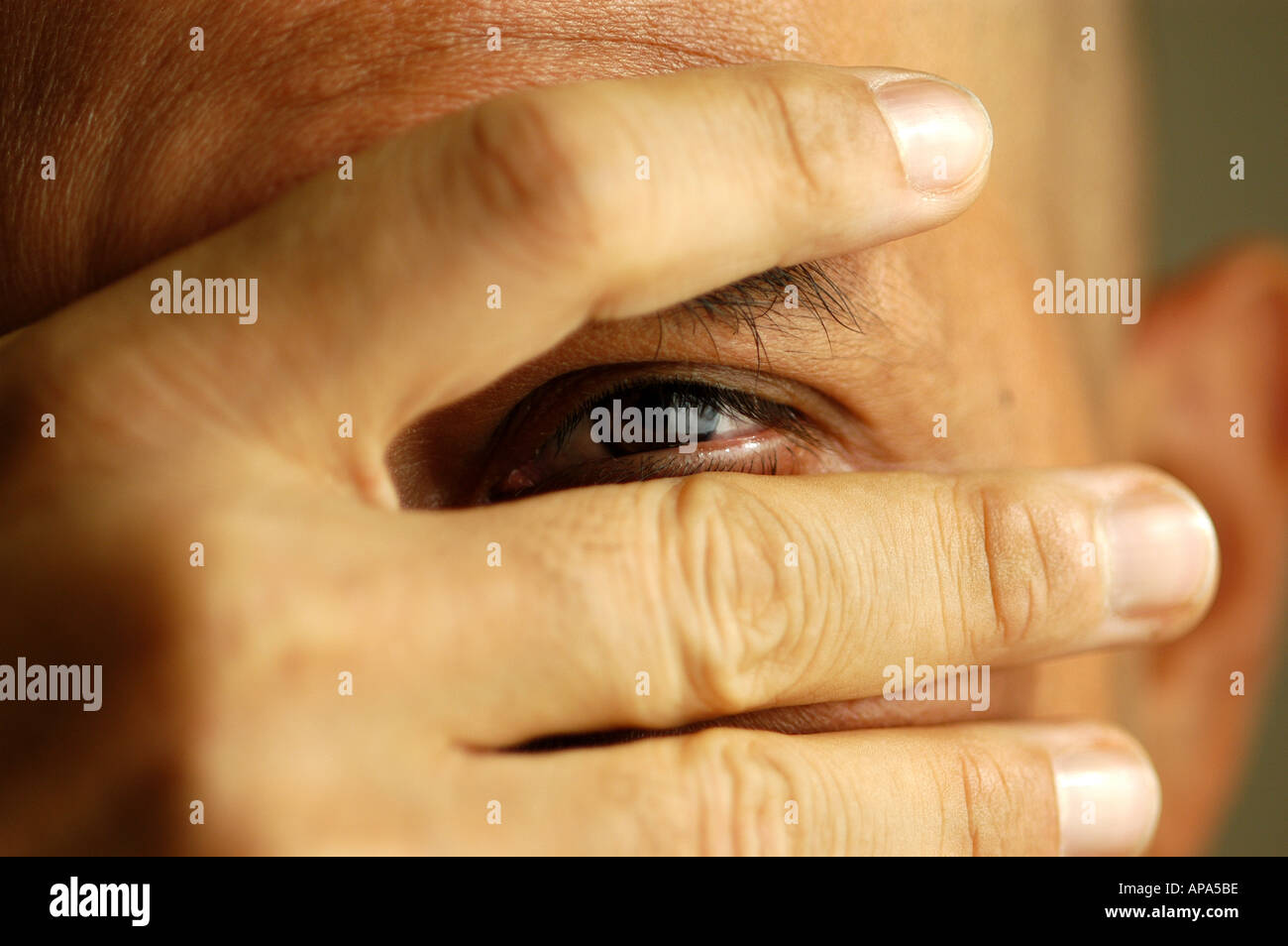 Left eye looking through fingers horizontally across face Stock Photo ...