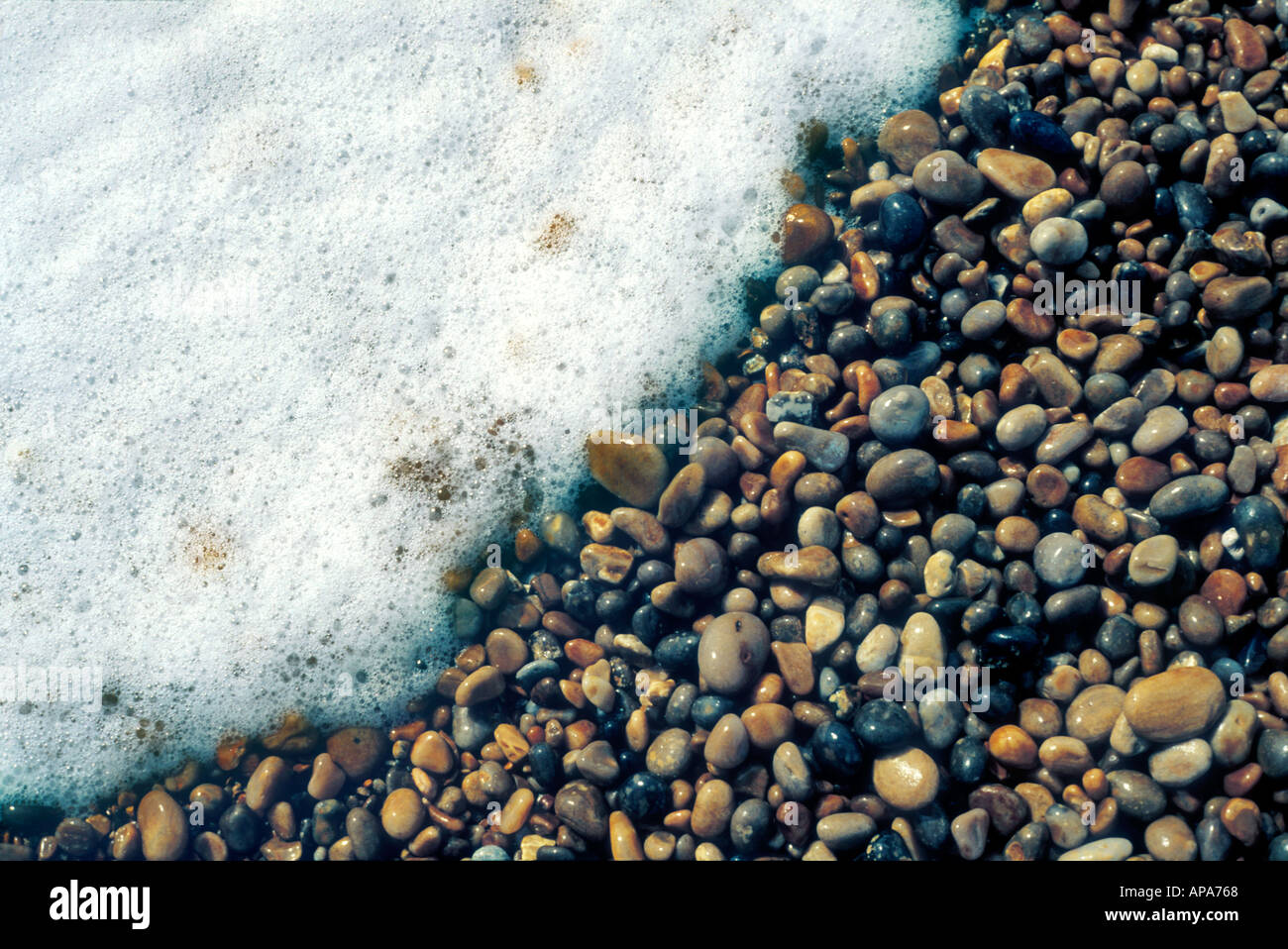 Foam and pebbles on a beach Stock Photo - Alamy