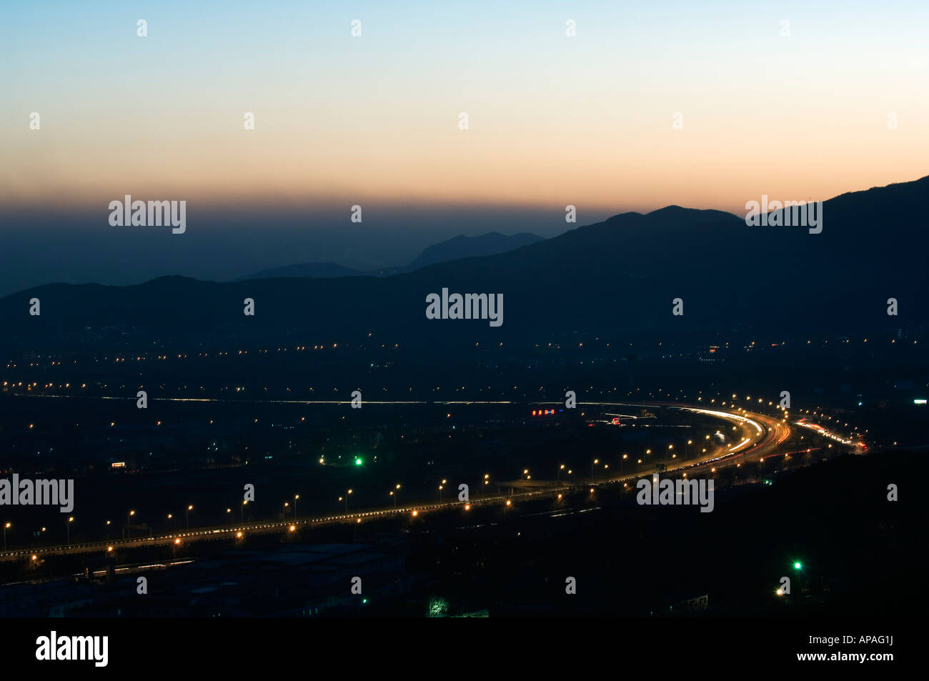 cars on a lit up highway at night below the western hills, beijing ...