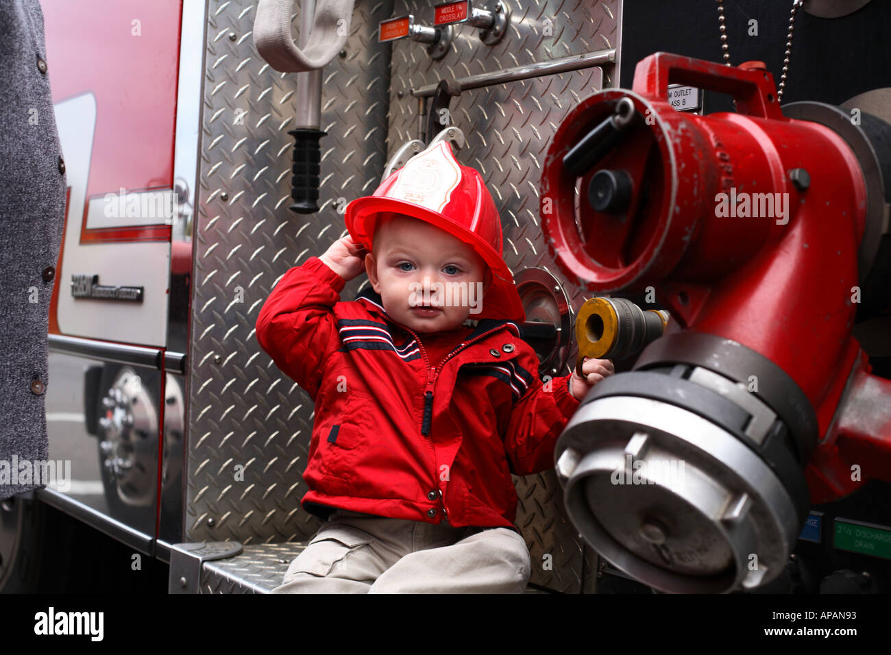 Toddler in firefighters hat sitting on fire truck Stock Photo - Alamy