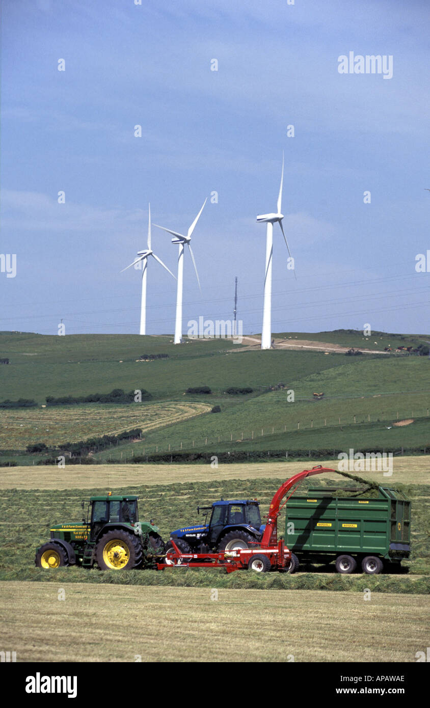 Farmer cutting silage off his fields with wind turbines behind near ...