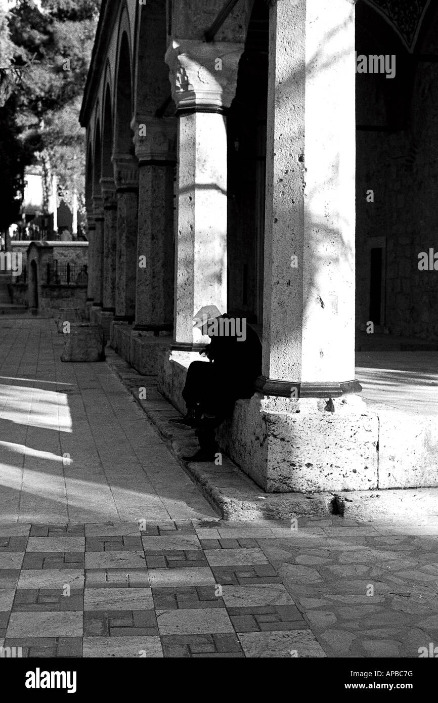 Black and white photo of a veiled man sitting in front of Islam temple ...