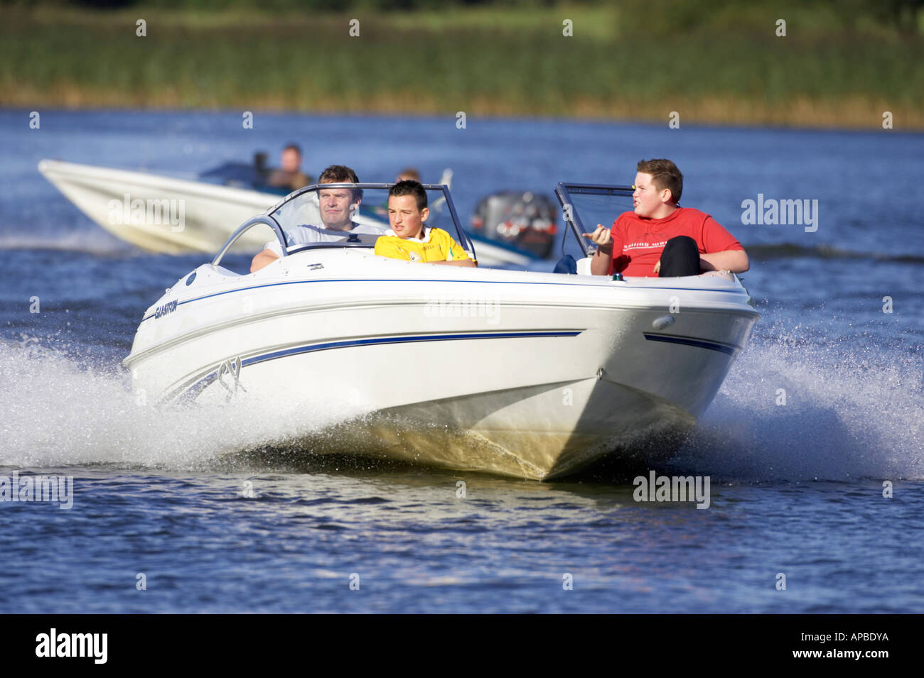 man and two teenage boys on board a glastron SX speed boat at speed on ...