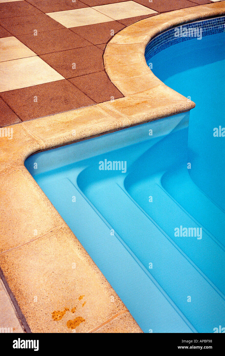Curved end of an outdoor swimming pool showing steps leading into blue ...