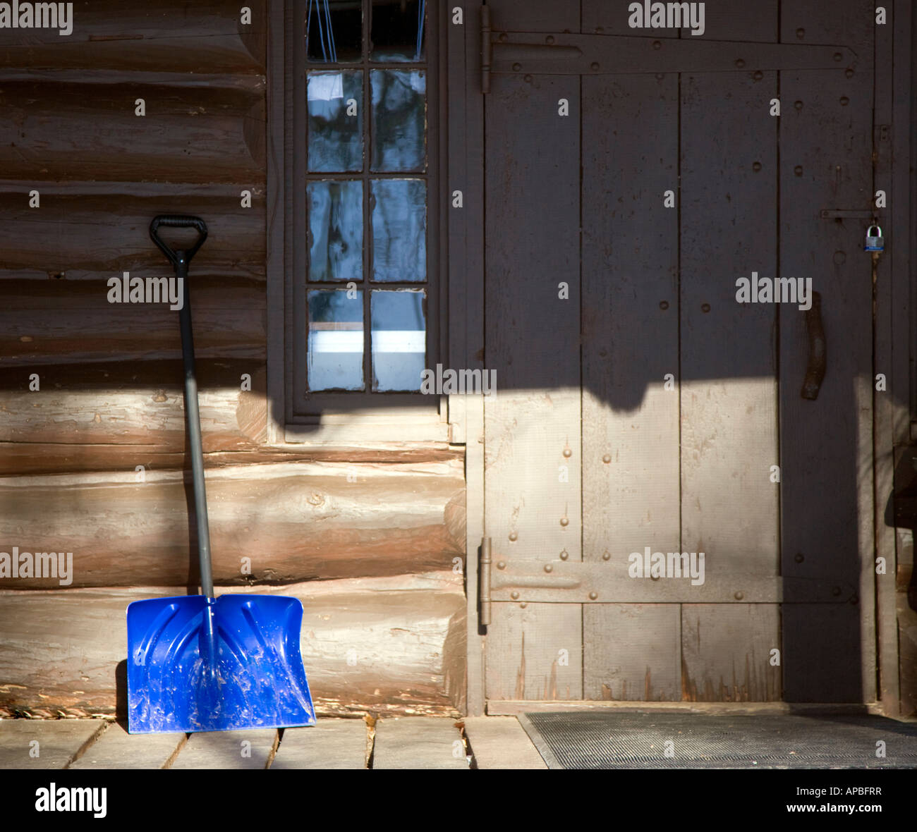 Snow shovel outside a log cabin Stock Photo - Alamy