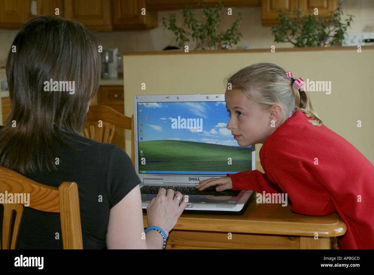 A girl helping her mother on a laptop computer Stock Photo - Alamy