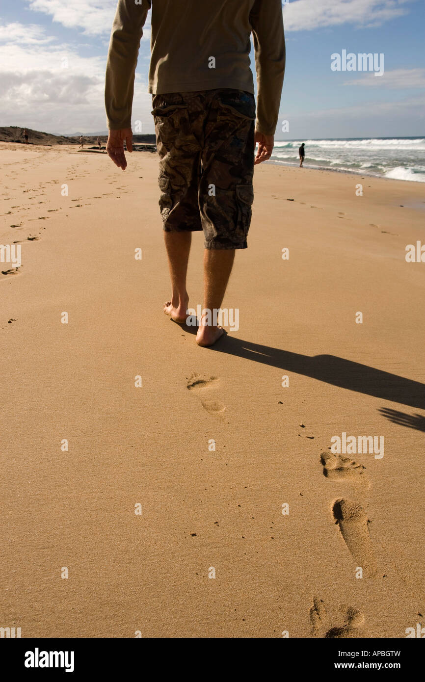 Young man walking calmly for the sand of the beach Stock Photo - Alamy