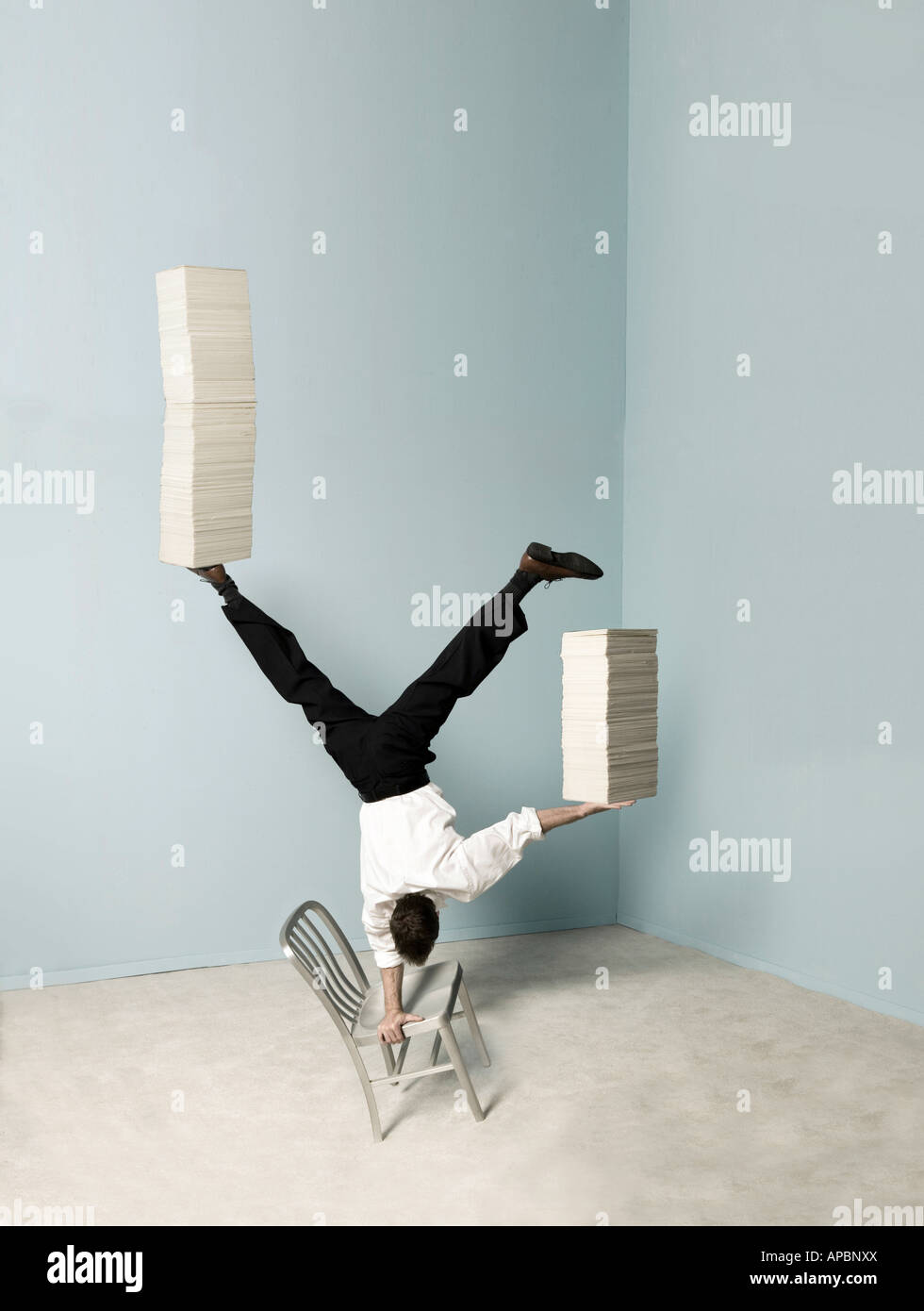 business man balances stacks of papers while doing a handstand on a ...