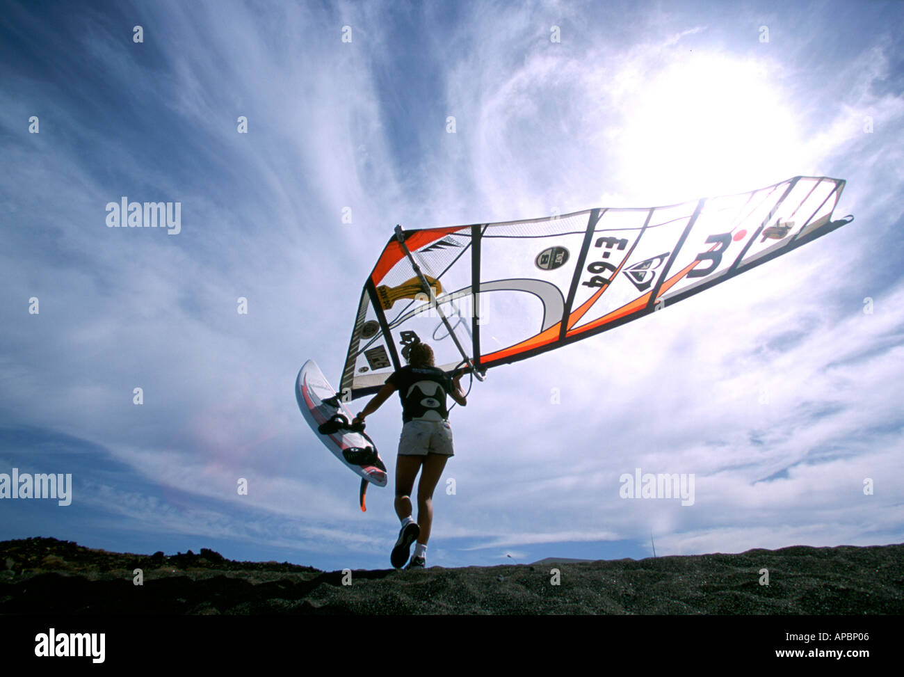 Female windsurfer carrying sail and board Stock Photo - Alamy