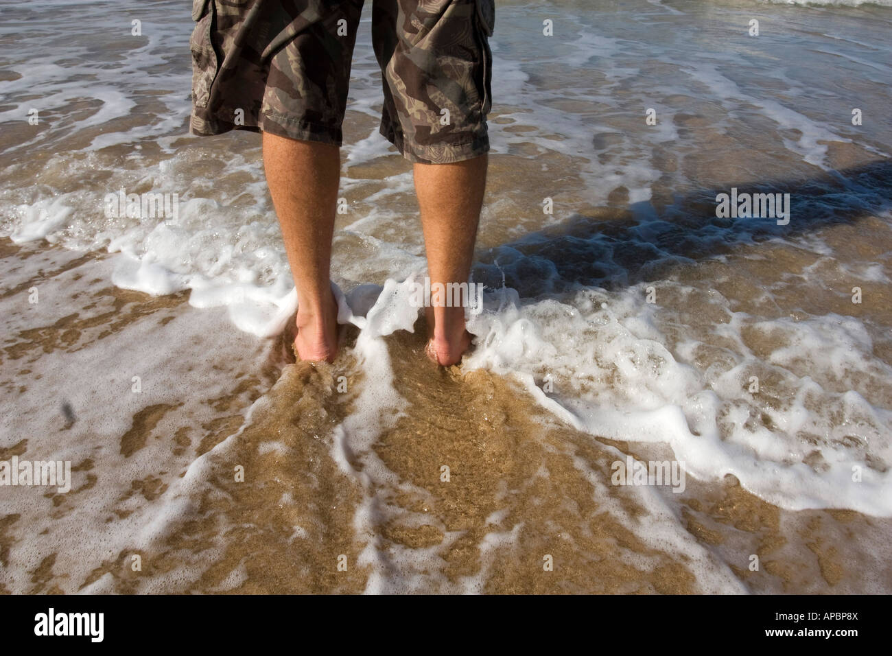 Young man wetting the feet in the water of the sea Stock Photo - Alamy