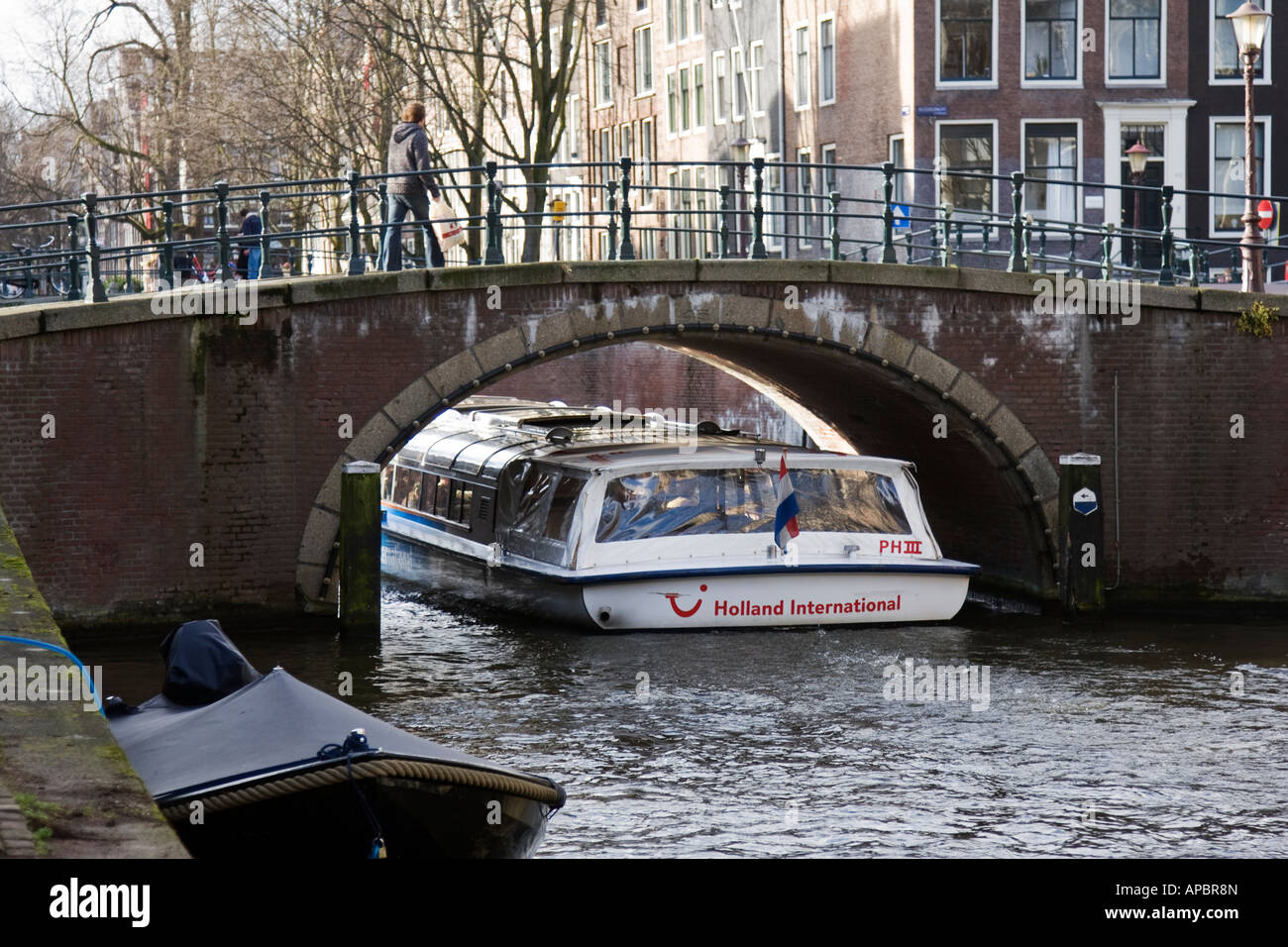 Tour boat under bridge in canal in Amsterdam Holland Stock Photo - Alamy
