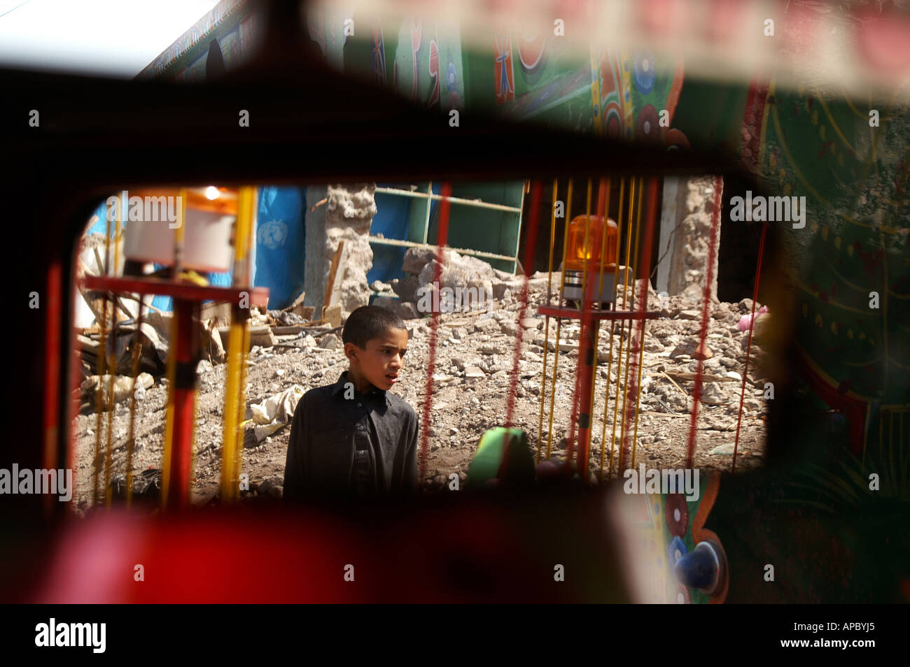 Boy standing in front of a collapsed building in Chinari near ...