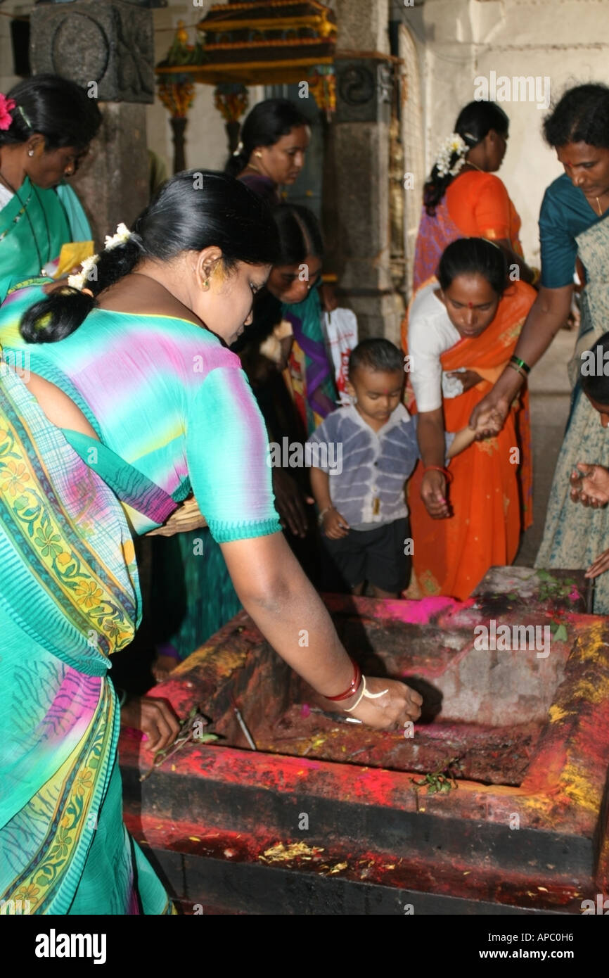 Hindu Women and children collecting blessed sindur powder at a temple ...