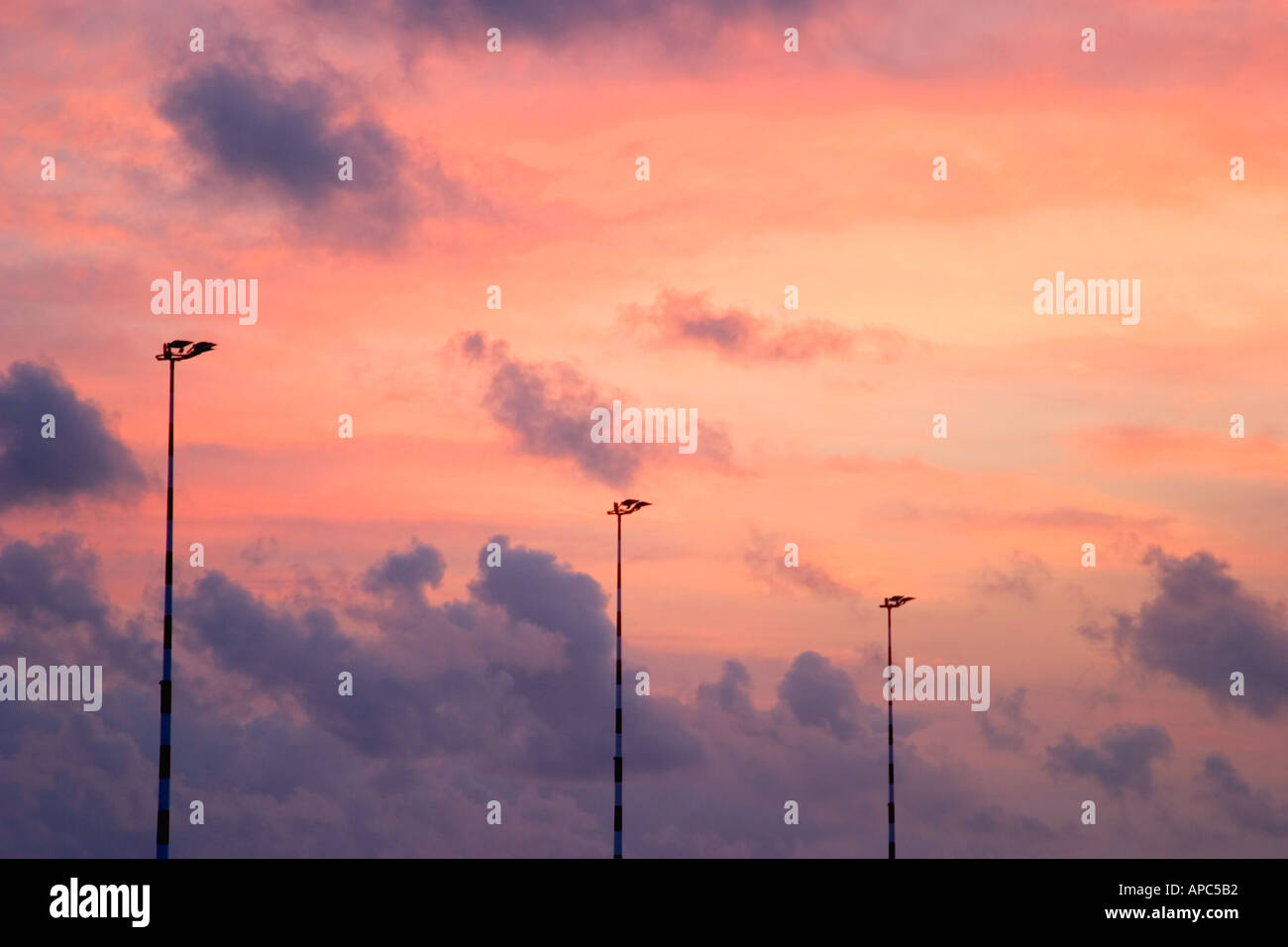 Light towers against dramatic sunset sky Stock Photo - Alamy