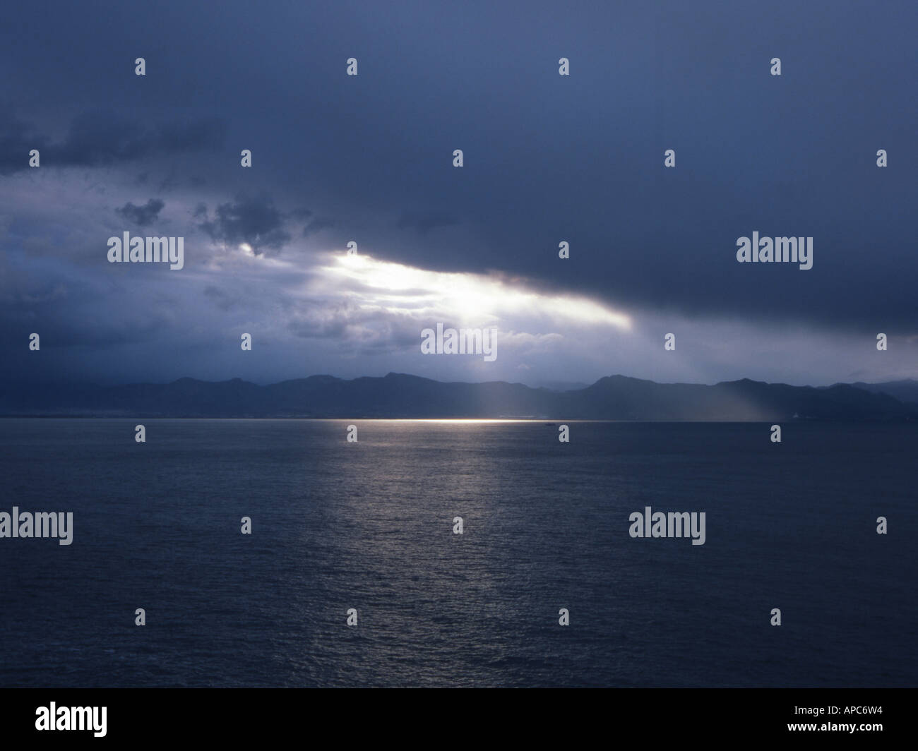 seascape of dark dramatic clouds above water with mountains in the ...