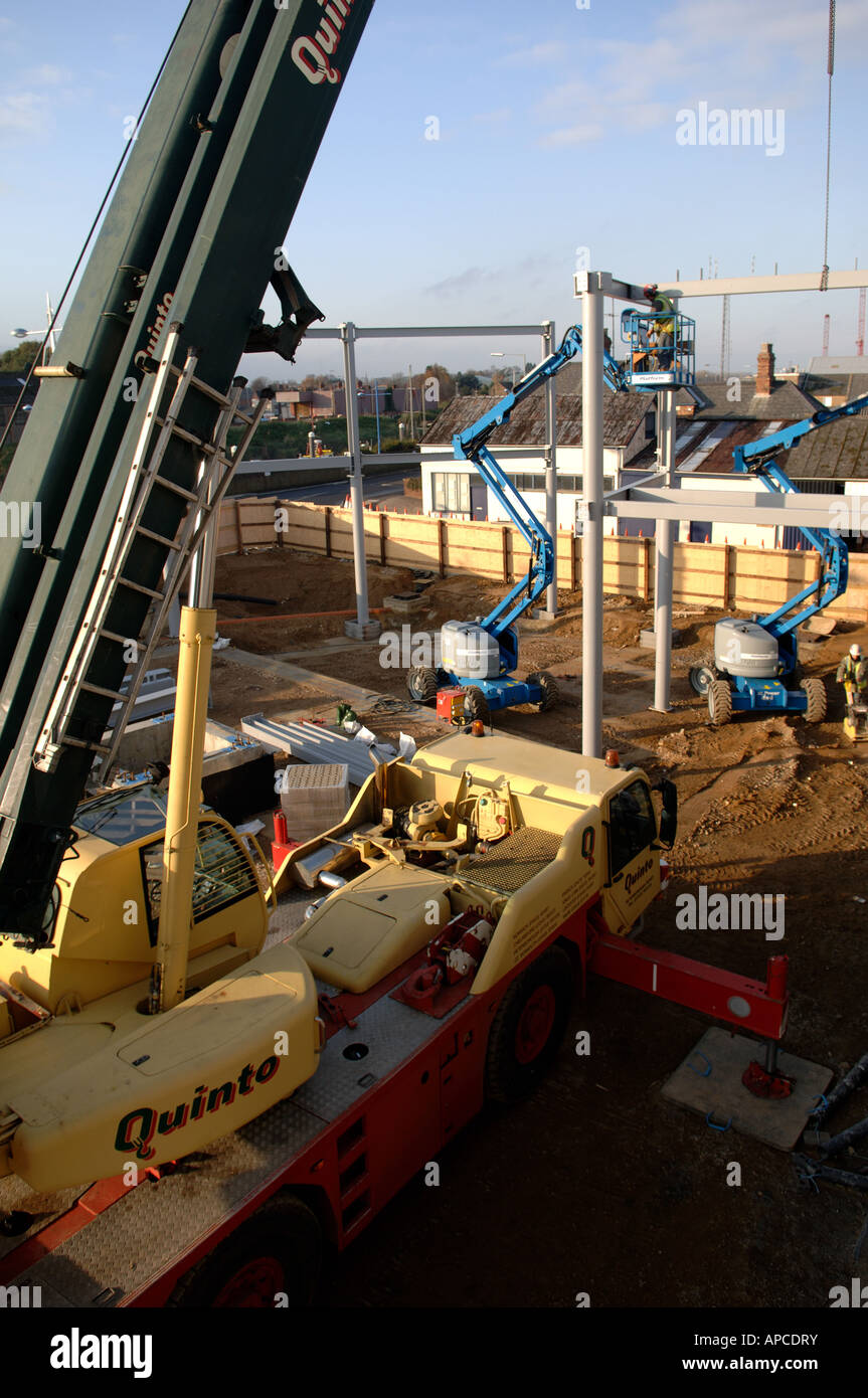 Crane lowering steel girder into position on steel fabricated building ...
