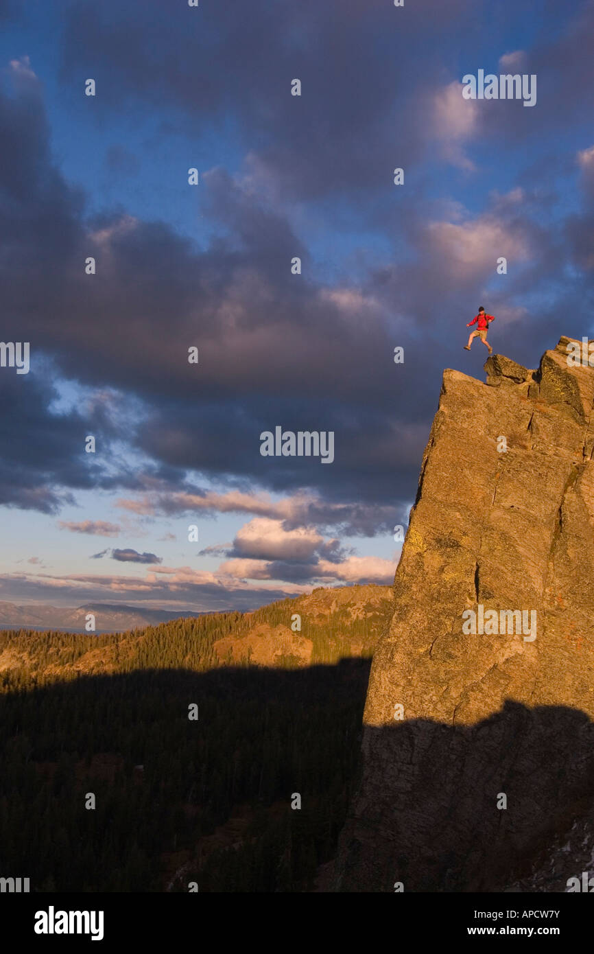 A man jumping on the edge of a cliff at sunset above Lake Tahoe in ...
