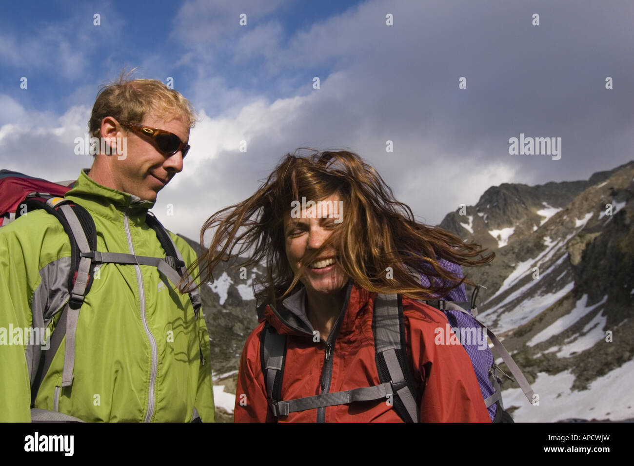 A woman tossing her hair as her boyfriend looks on while hiking near ...