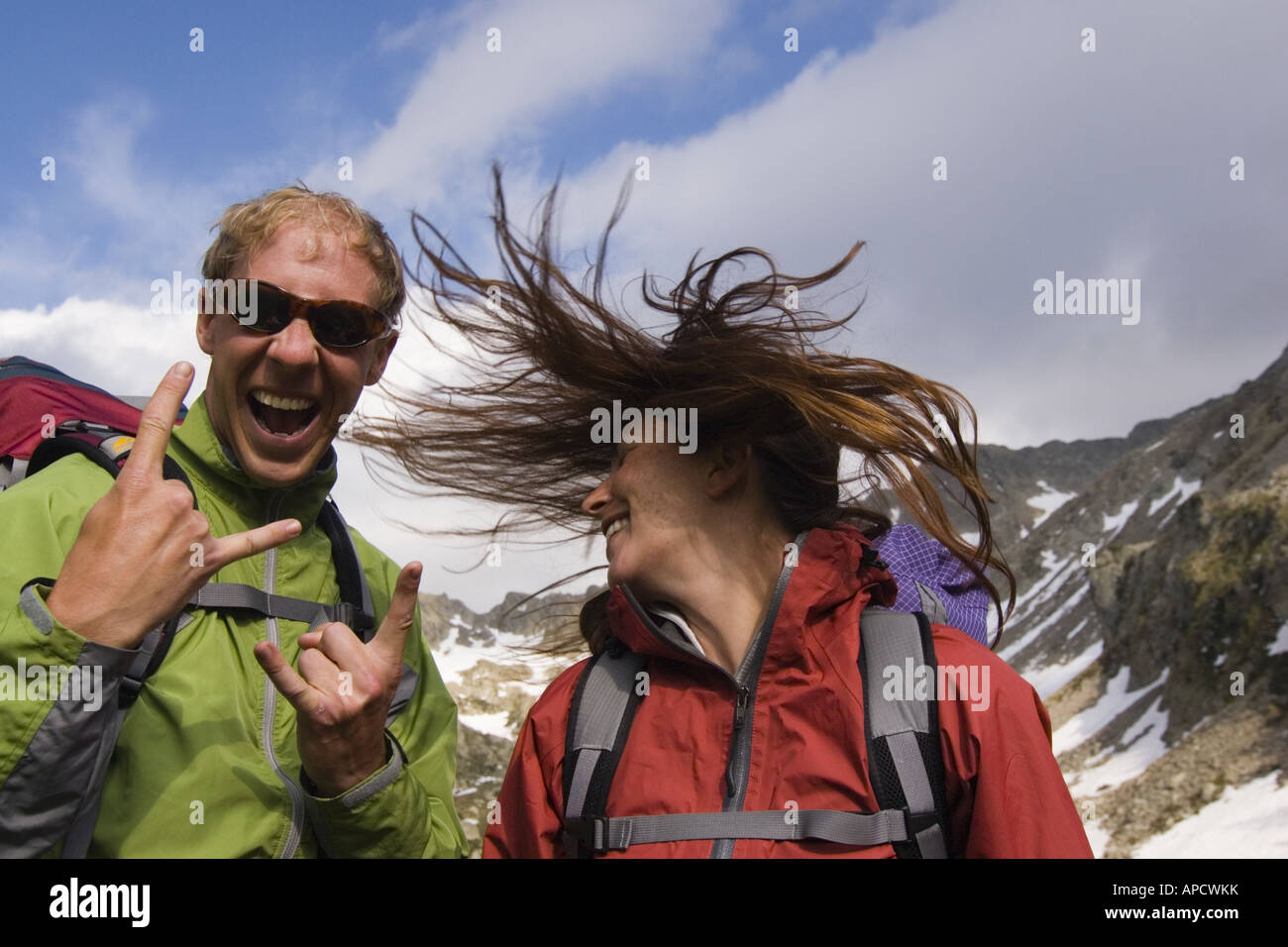 A woman tossing her hair as her boyfriend looks on while hiking near ...