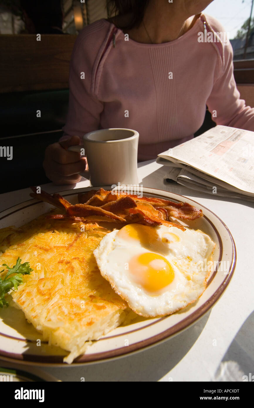 A woman eating breakfast and reading a newspaper in a diner in Truckee ...