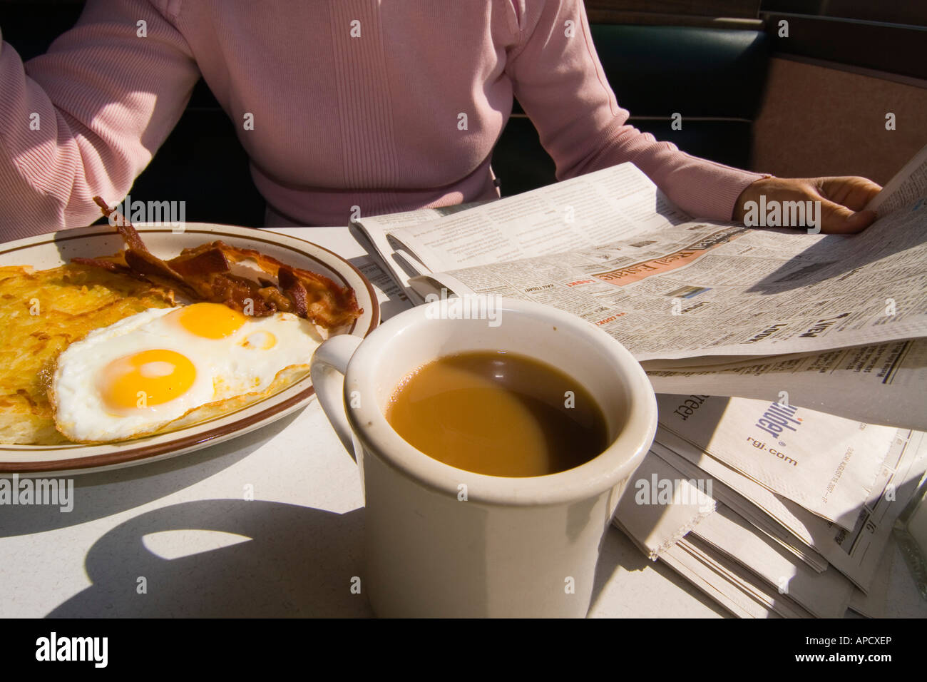 A woman eating breakfast and reading a newspaper in a diner in Truckee ...