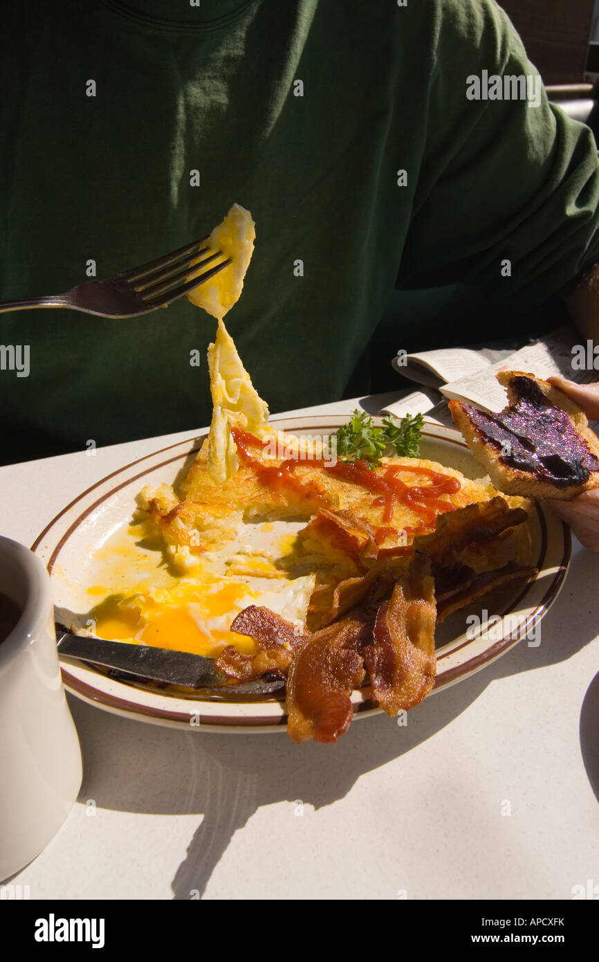 A man eating breakfast and reading a newspaper in a diner in Truckee ...