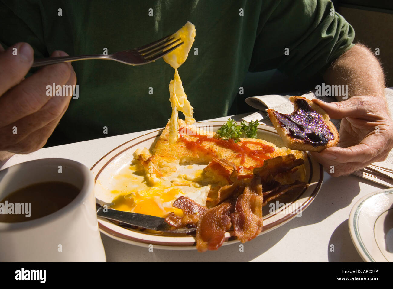 A man eating breakfast and reading a newspaper in a diner in Truckee ...