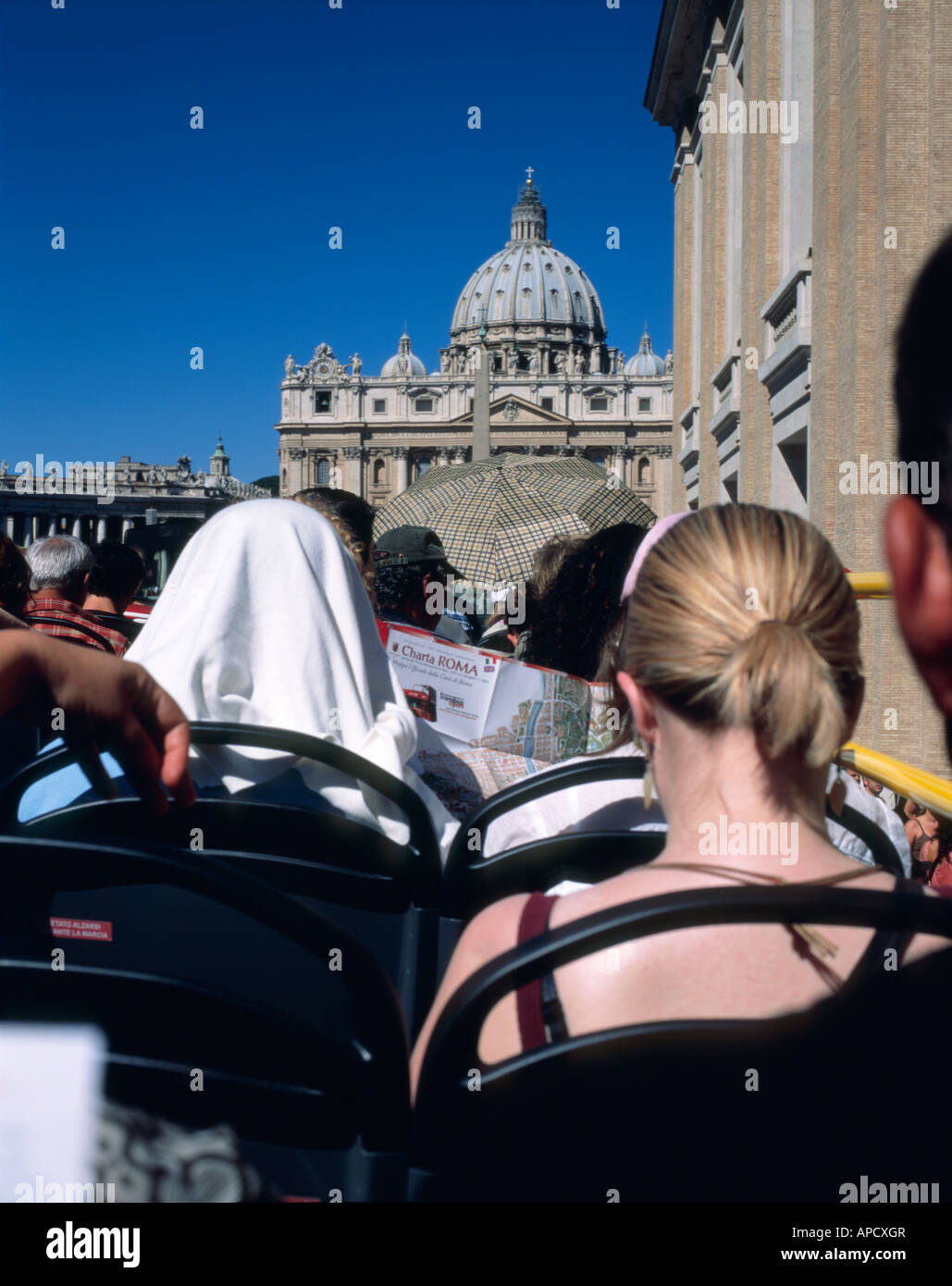 Tourists sitting on the top floor of an open double-decker bus with St ...
