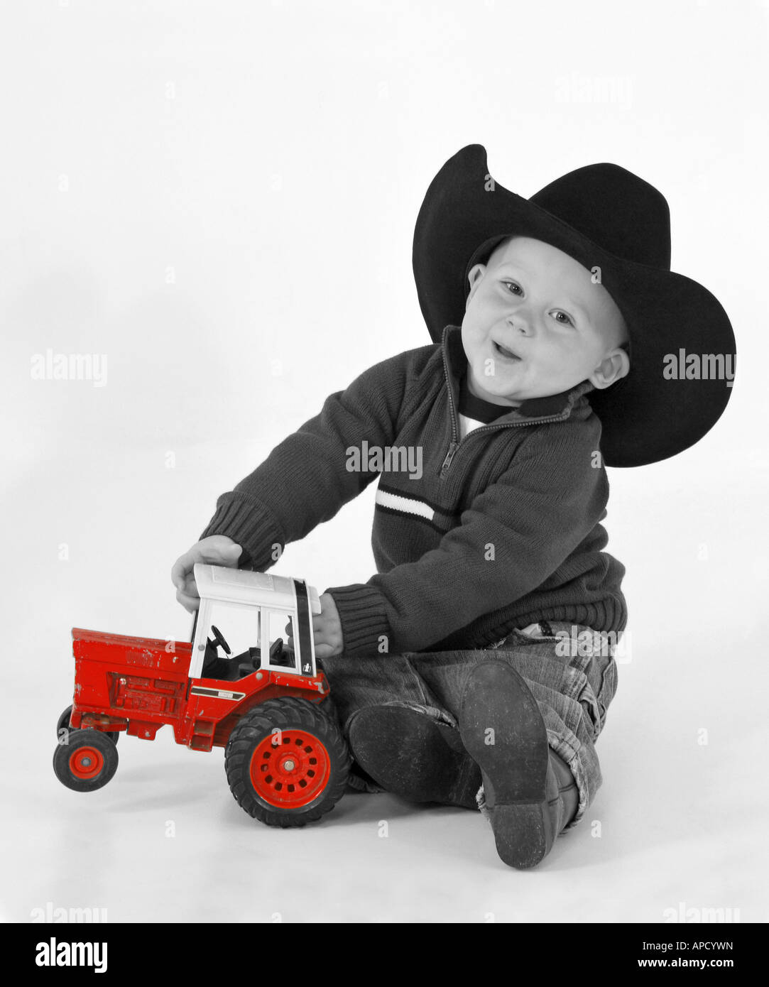 Small cowboy playing with red tractor Stock Photo - Alamy