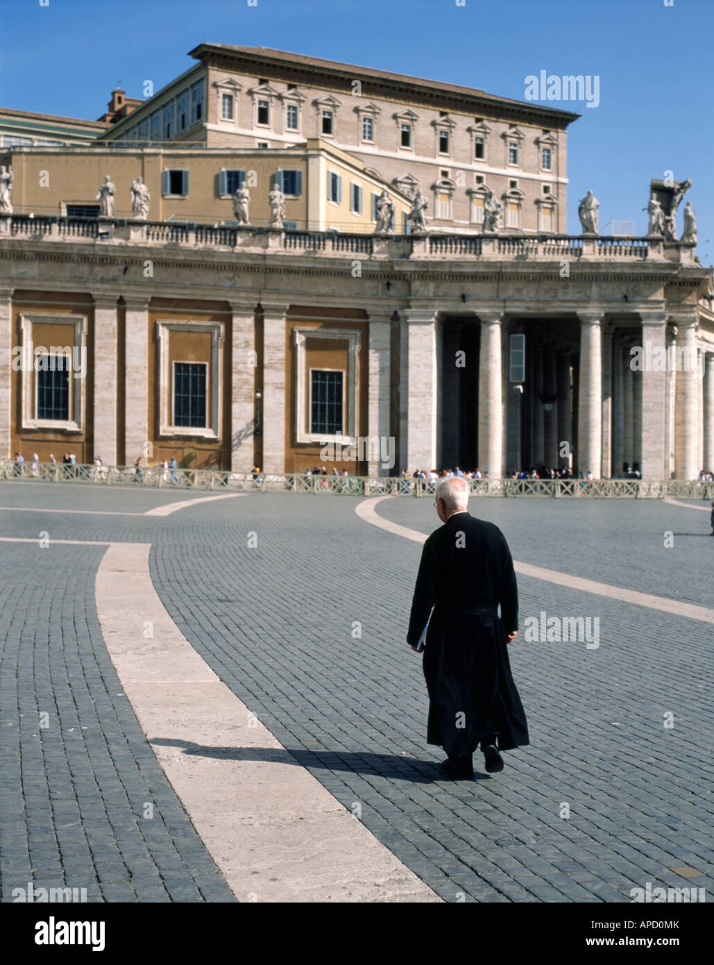 Black dressed single priest walking across St. Peter's Square with the ...
