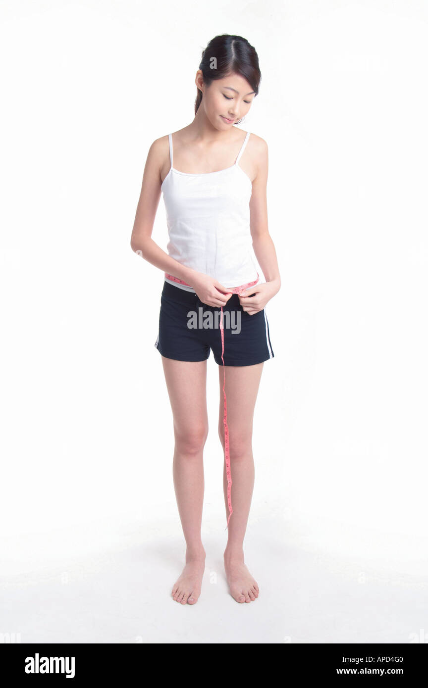 Young woman standing and measuring full length Stock Photo - Alamy