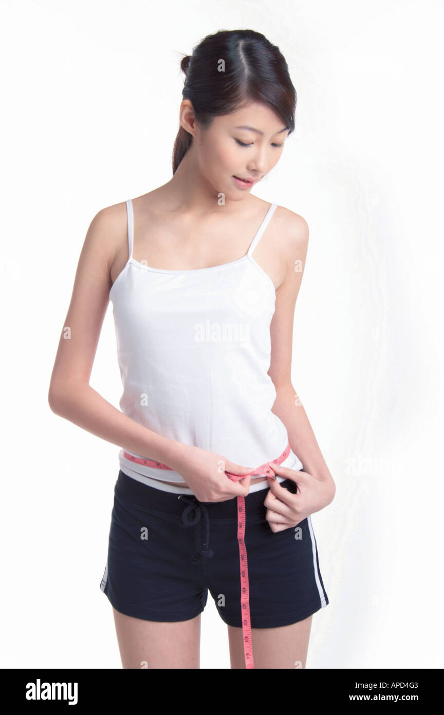 Young woman standing and measuring three quarter length Stock Photo - Alamy