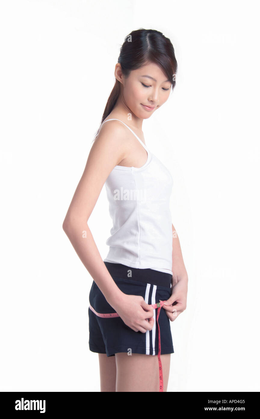 Young woman standing and measuring three quarter length side view Stock ...