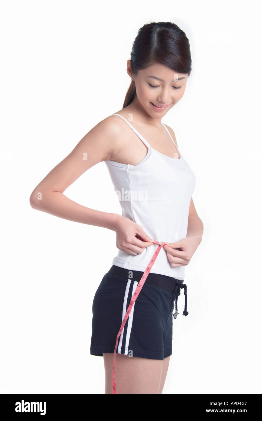 Young woman standing and measuring three quarter length side view Stock ...