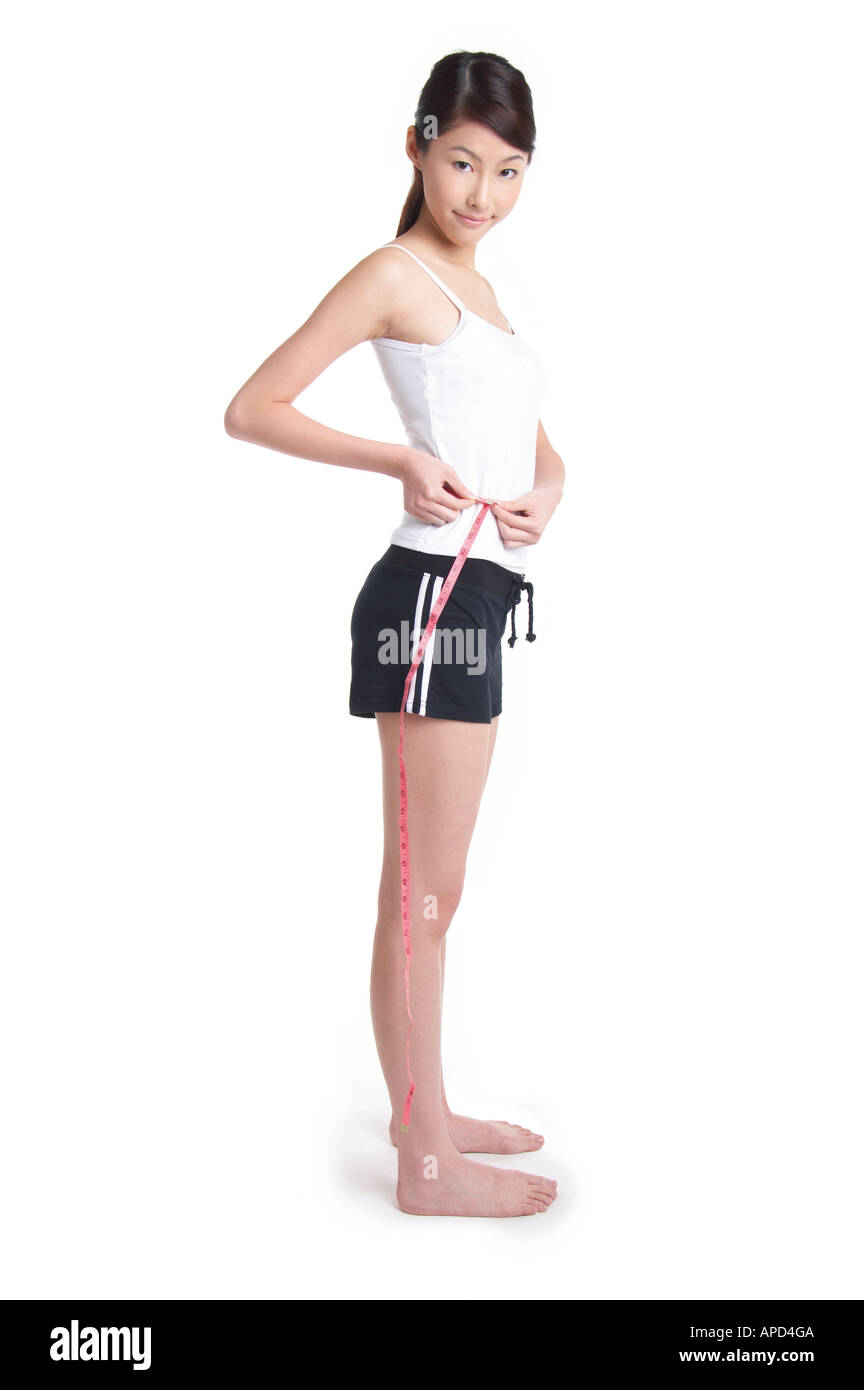 Young woman standing and measuring full length side view Stock Photo ...