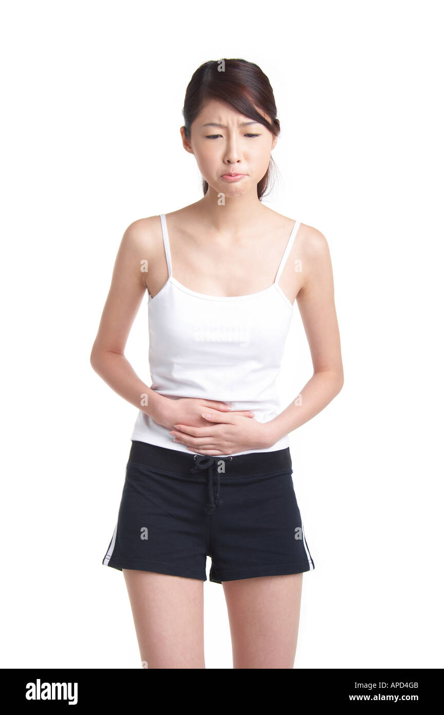 Young woman standing with hands on abdomen Stock Photo - Alamy