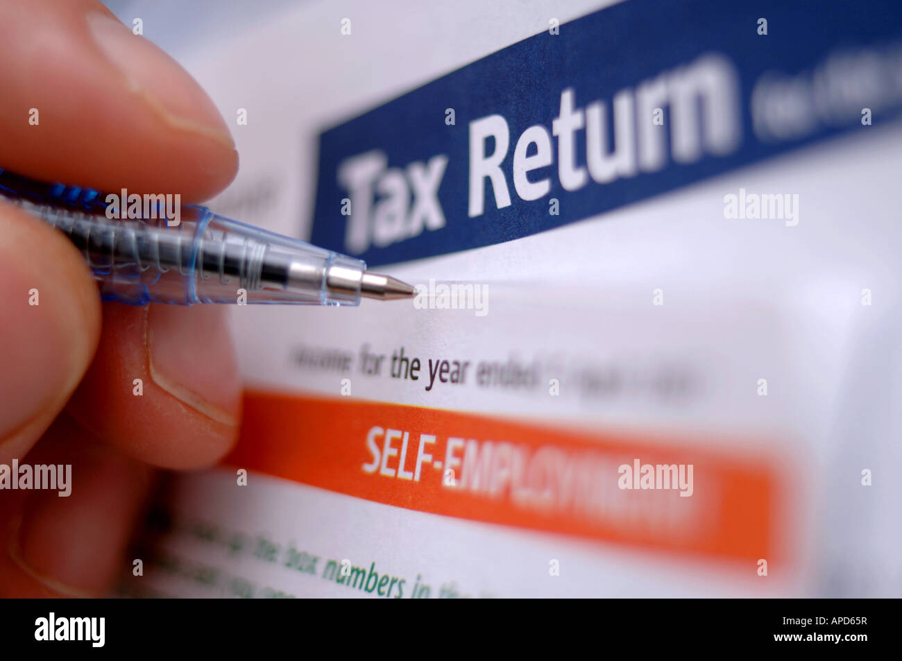 A hand seen filling in the Tax Return form using the tax return guide ...