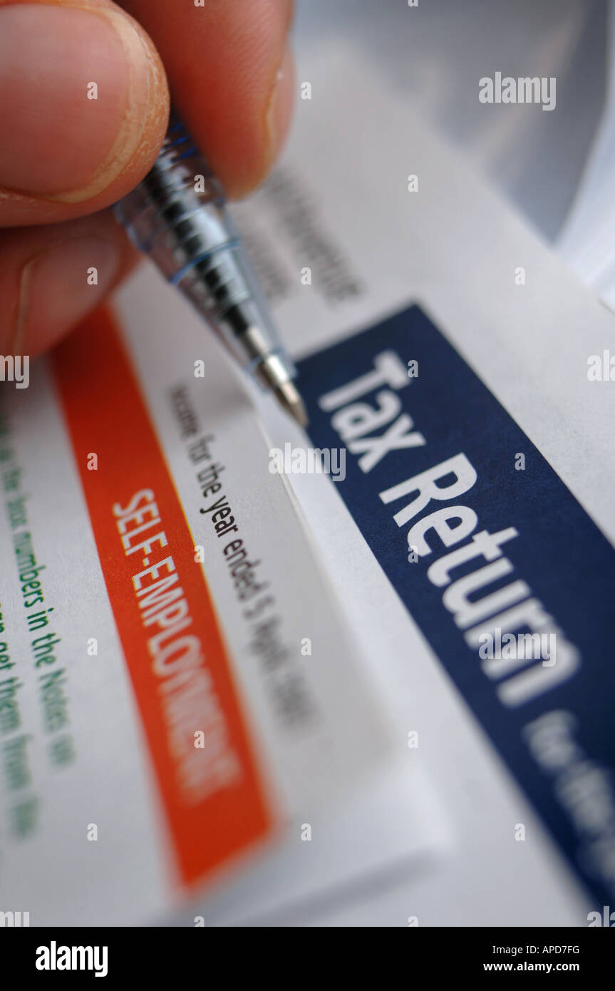 A hand seen filling in the Tax Return form using the tax return guide ...