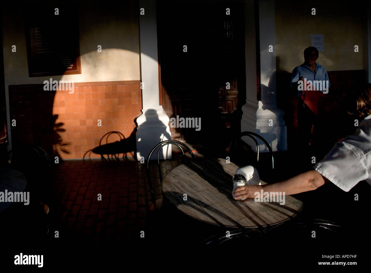 Mexico Oaxaca Morning sun casts shadow of waitress setting up tables at ...