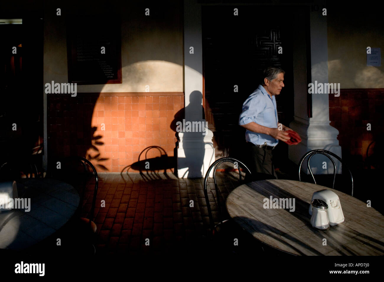 Mexico Oaxaca Morning sun casts shadow of waiter setting up tables at ...