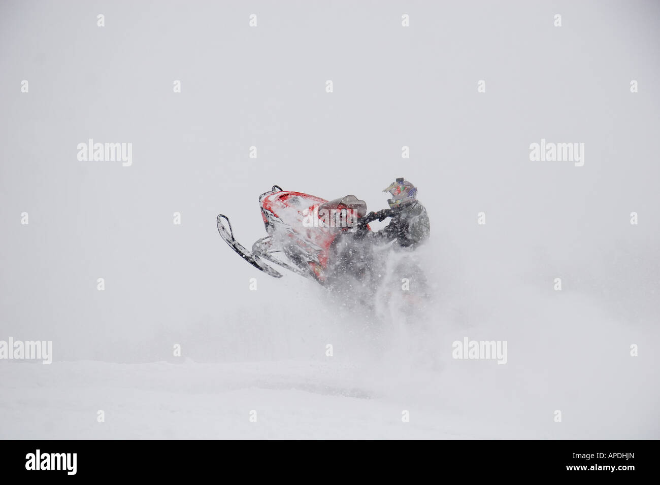 A snowmobiler jumps from a hill on a snowy day Stock Photo - Alamy