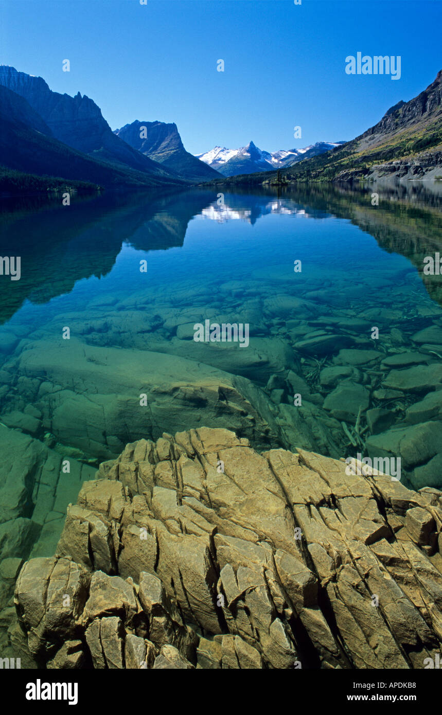 Rocks smoothed by glaciers flow into mirror smooth Lake Saint Mary ...