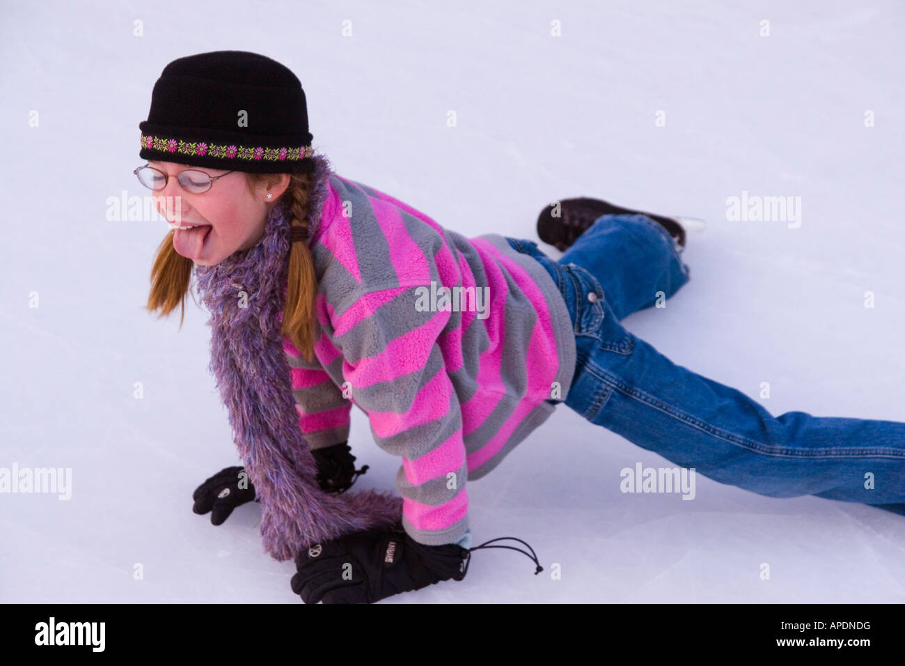 A smiling young girl lying on the ice at a skating rink at Northstar ...