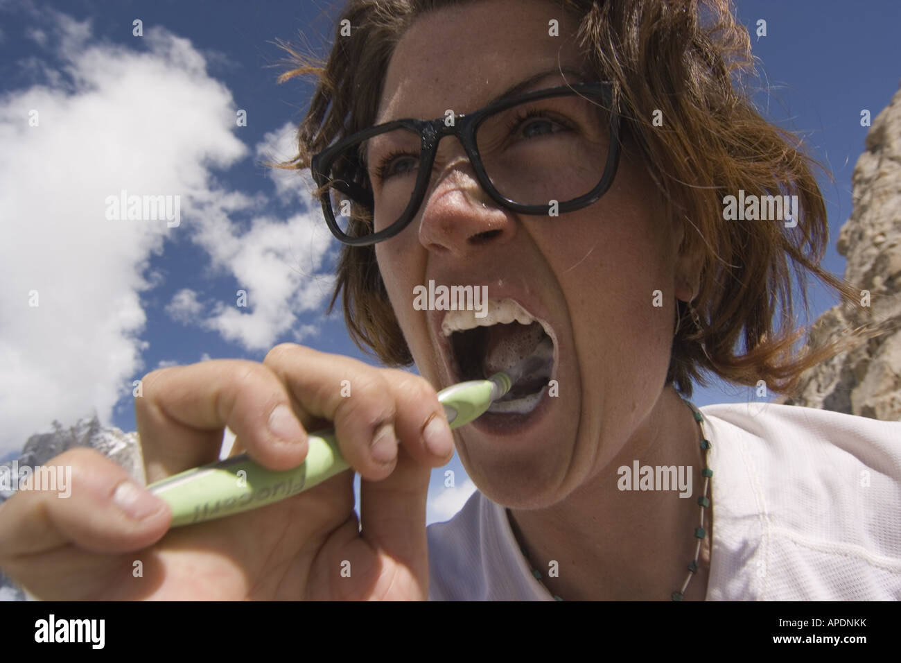 A woman with messy hair brushing her teeth while camping on the Biafo ...