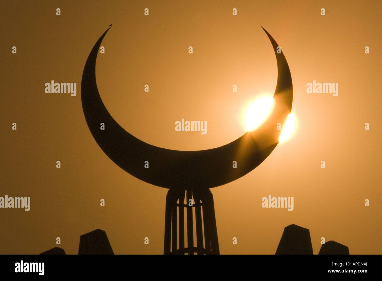 The sun shining on a silhouetted Muslim crescent at the Faisal Mosque ...