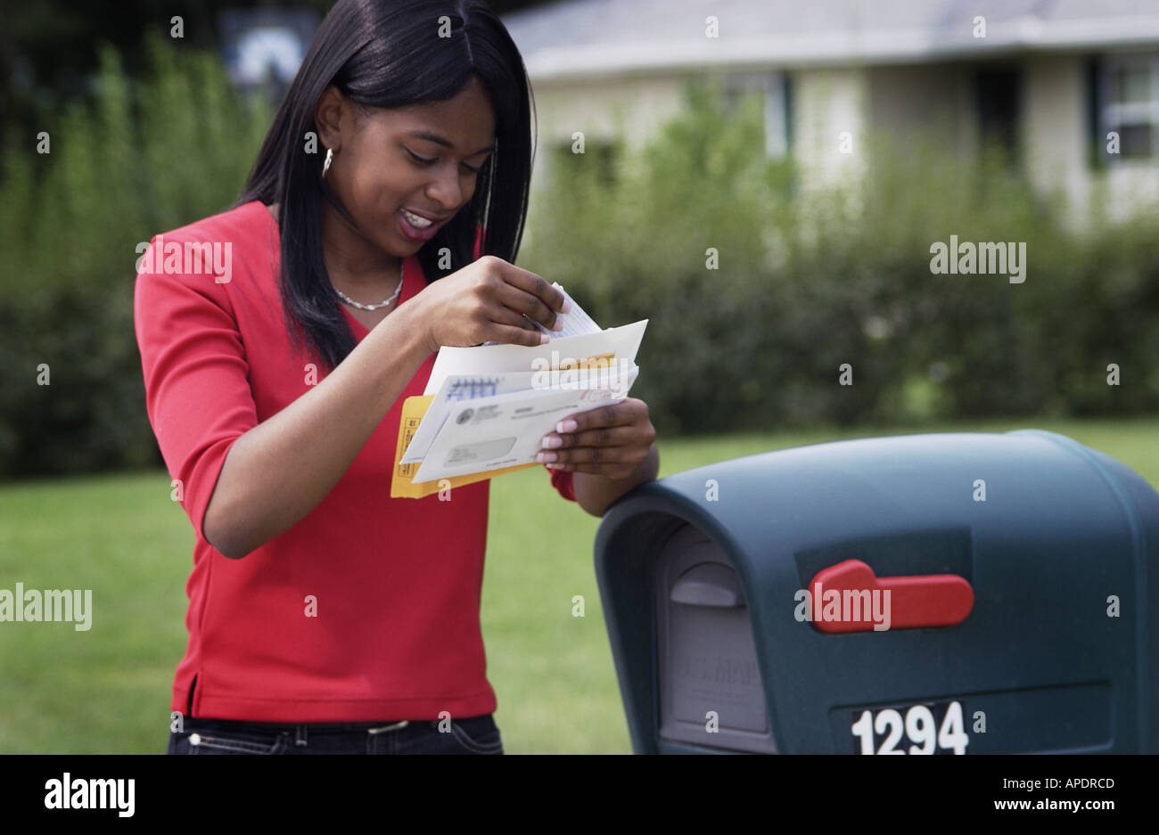 African American woman getting mail from mailbox Stock Photo - Alamy