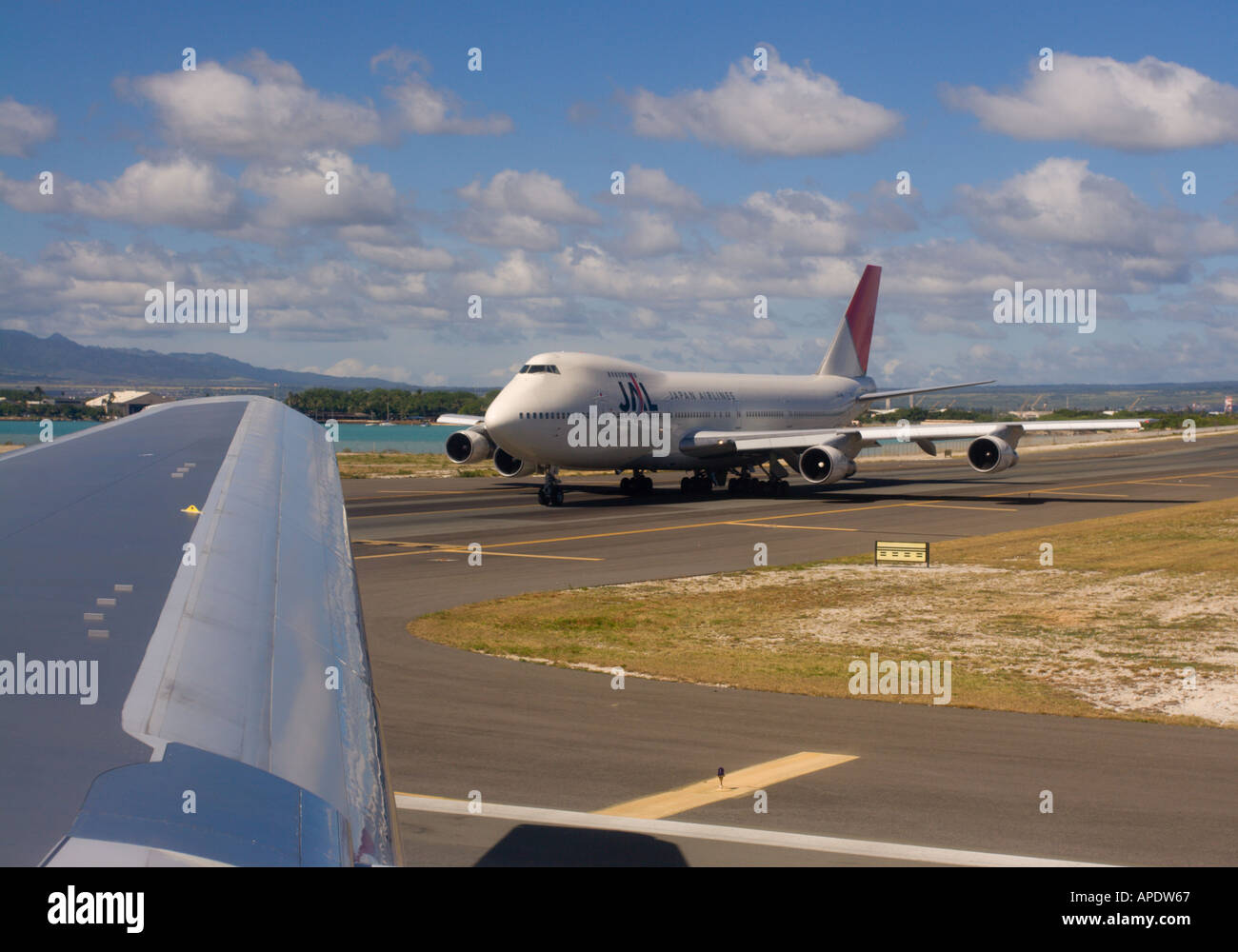 View along wing of airliner to a white and red Boeing 747 jumbo jet of ...