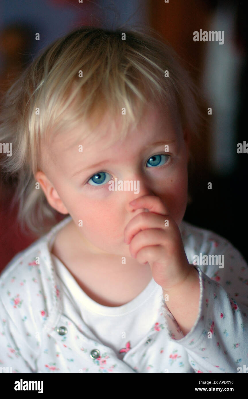 A Cute Blonde Girl Sucking Her Thumb Looking Tired While Wearing